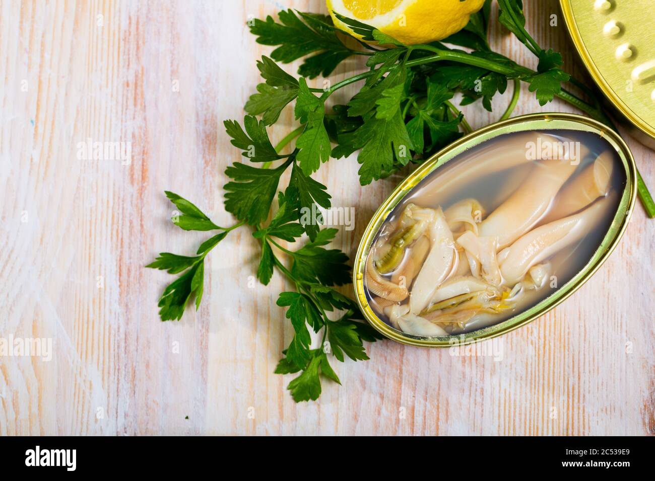 Seafood. Canned saltwater clams ensis in open tin can on wooden table ...