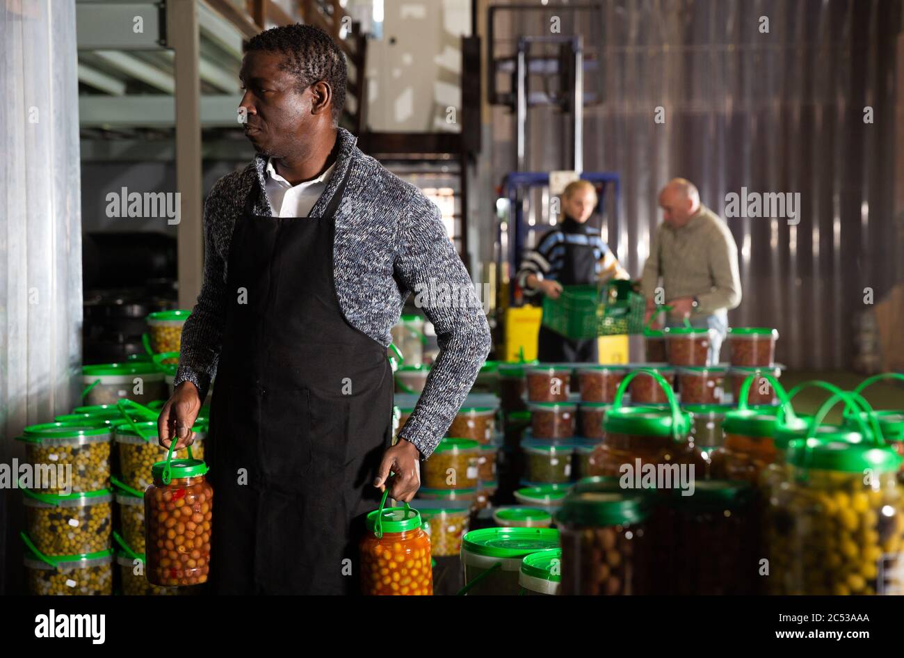 Afro-american male worker stocks plastic containers and cans with ...