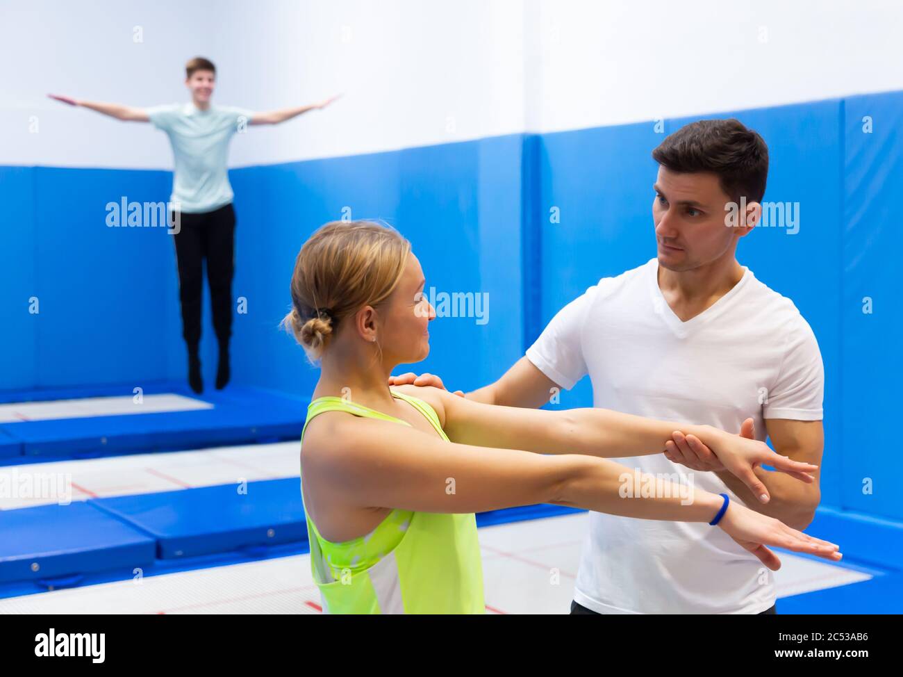 Portrait of man coach showing young woman jumping movements during ...