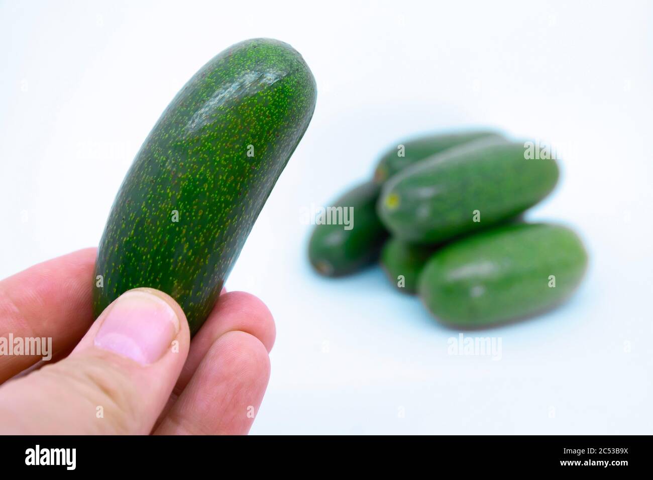 Mini avocados on white background Stock Photo - Alamy