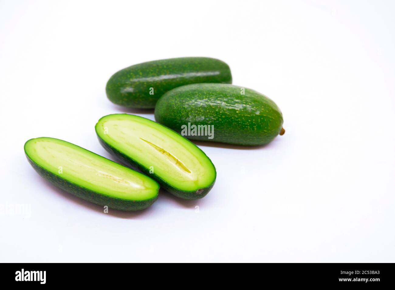 Mini avocados on white background Stock Photo - Alamy