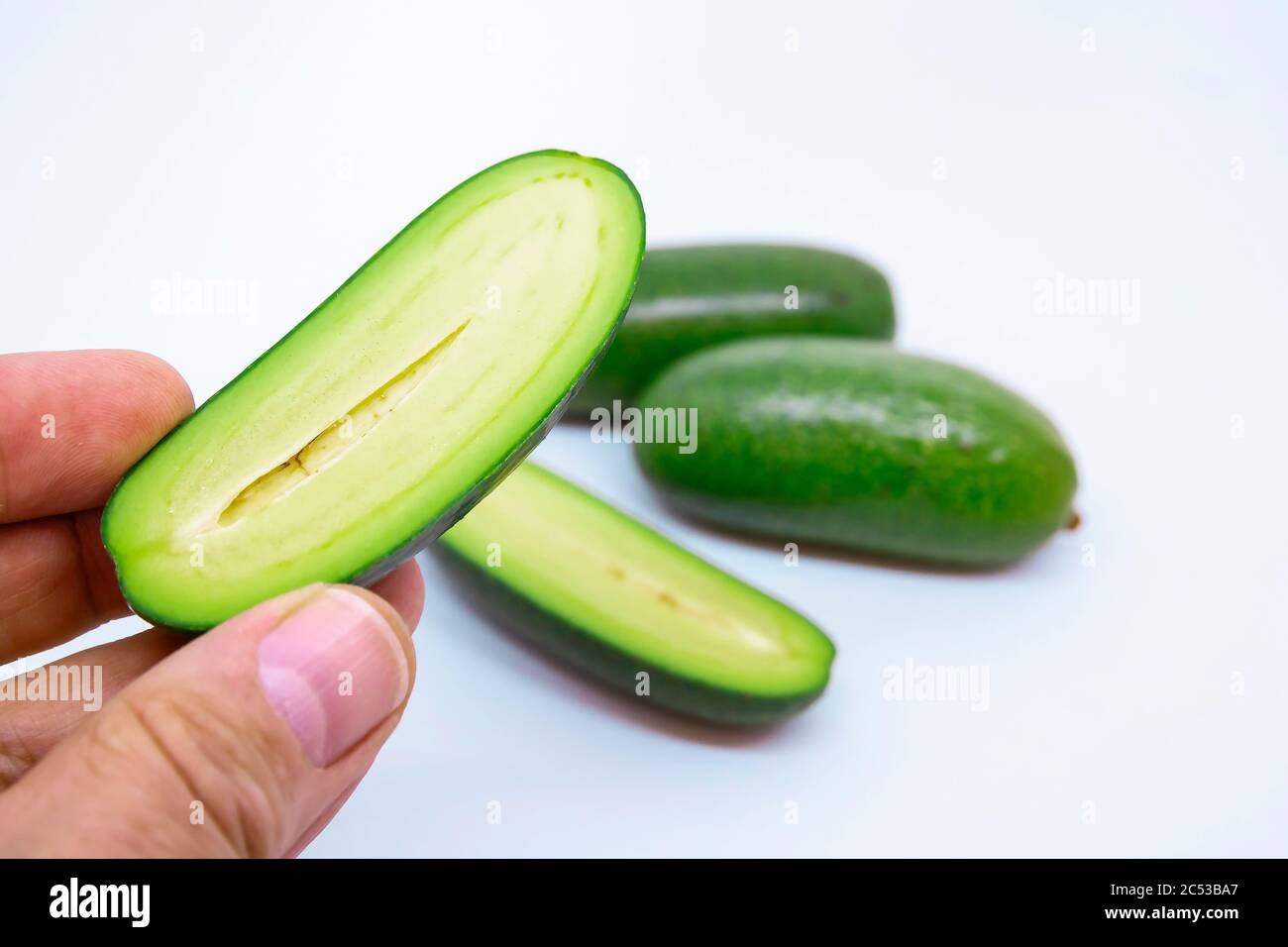 Mini avocados on white background Stock Photo - Alamy