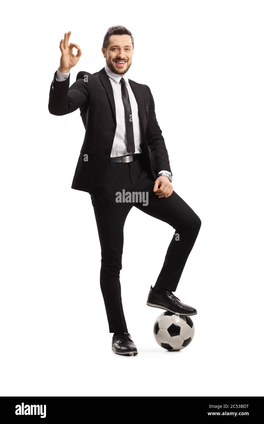 Full length portrait of a man in a black suit with his leg on a soccer ...