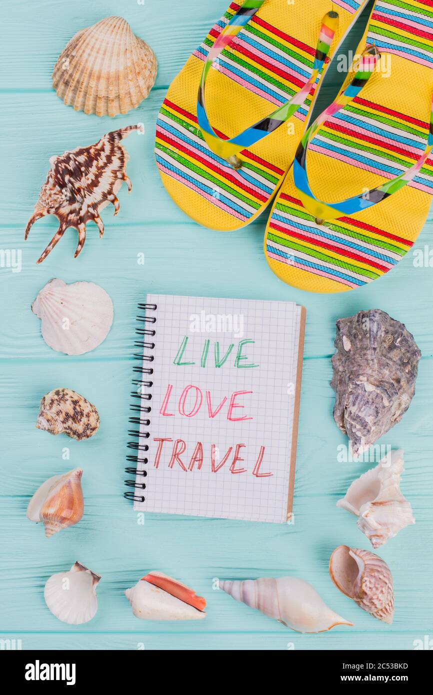 Different sea shells and yellow sandals in the corner on turquoise ...