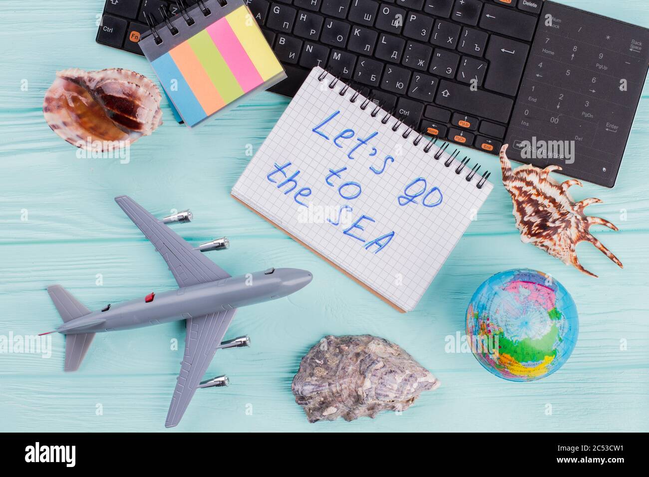Summer travel accessories consist of seashells, airplane, globe on blue ...