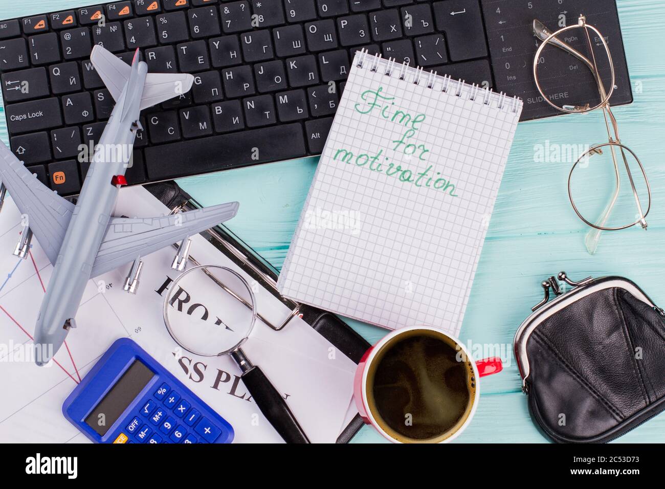 Time for motivation on notebook with office accessories and airplane on ...