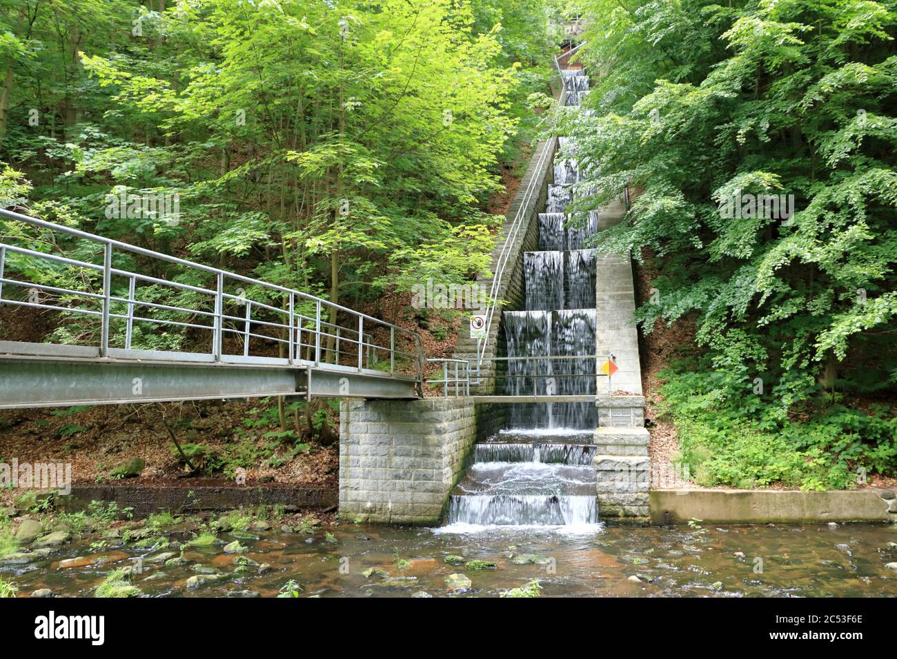mountain river in the forest with a waterfall and concrete wall near ...