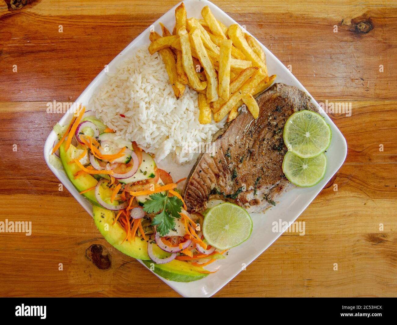 Grilled fish served with vegetable salad, rice, and fried potatoes ...