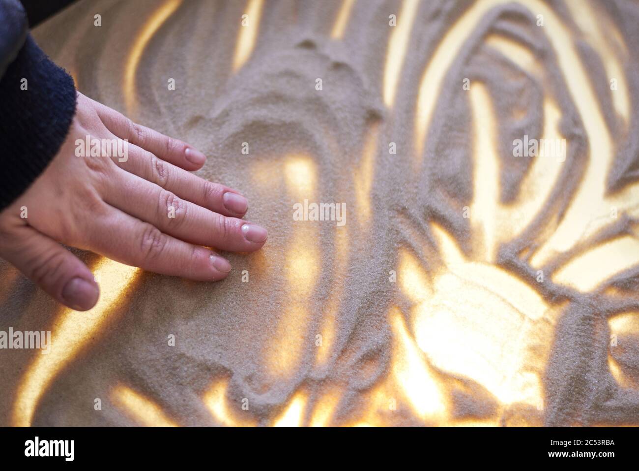 The girl's hand draws on the sand, close-up Stock Photo - Alamy