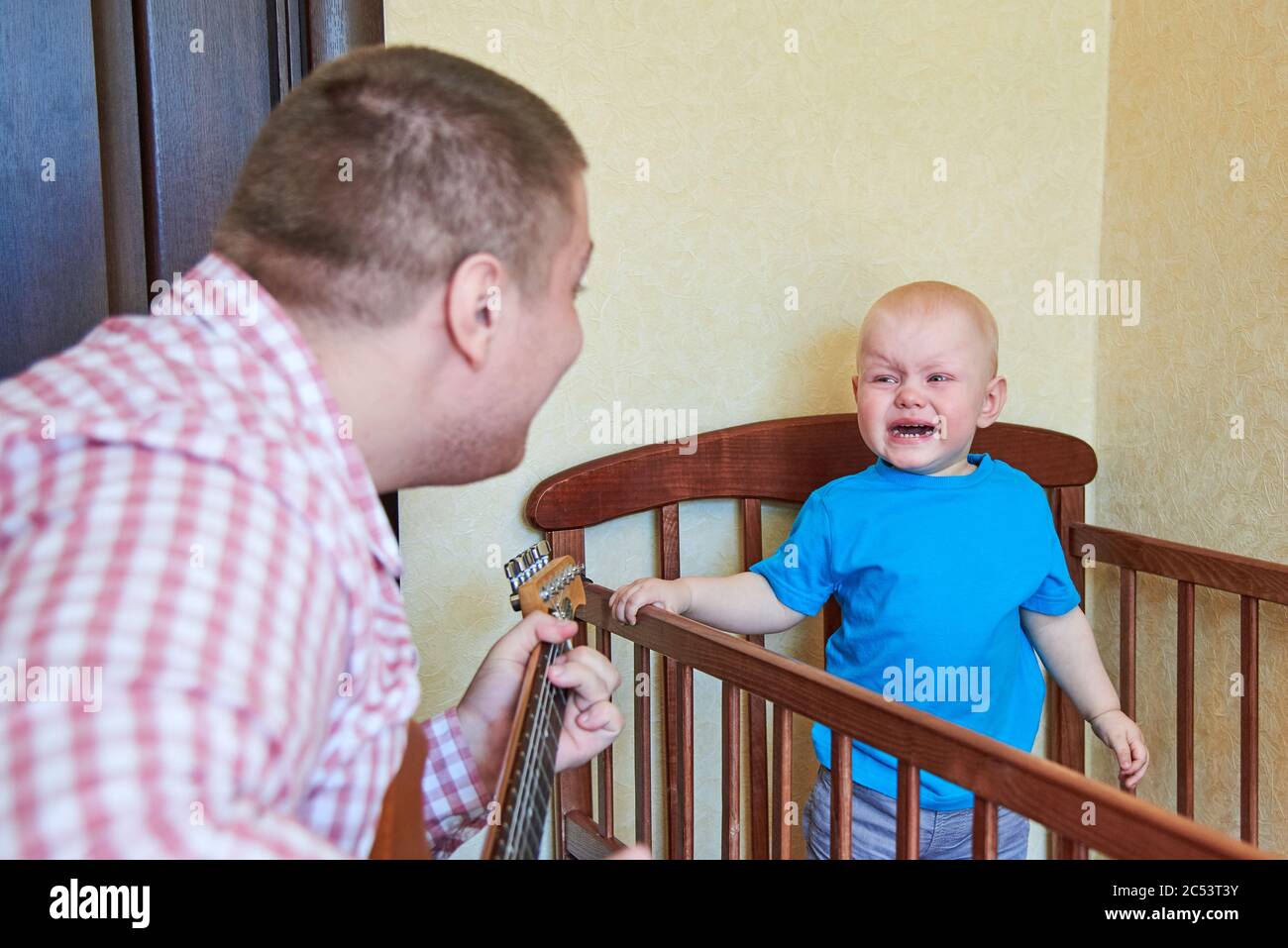 Dad plays guitar to console his crying little son Stock Photo - Alamy