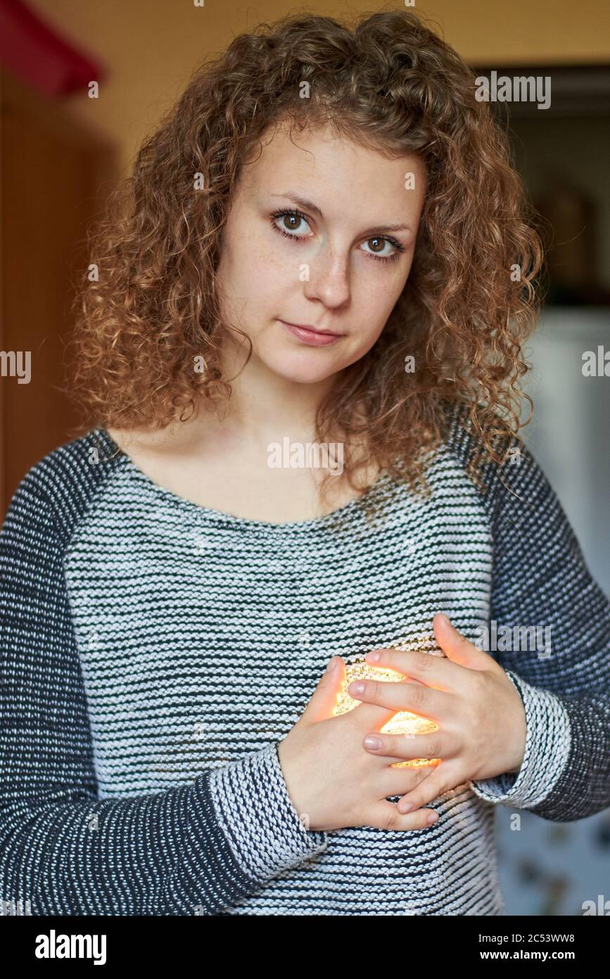 A woman holds folded hands in the area of the heart through which the ...