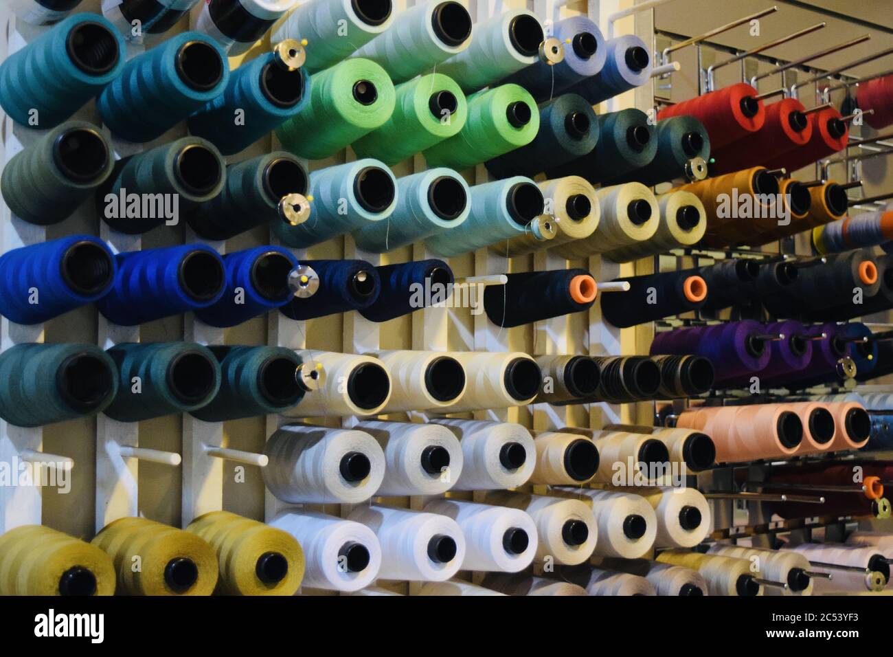 Sewing shop with colorful spools of sewing thread hanging on the wall ...