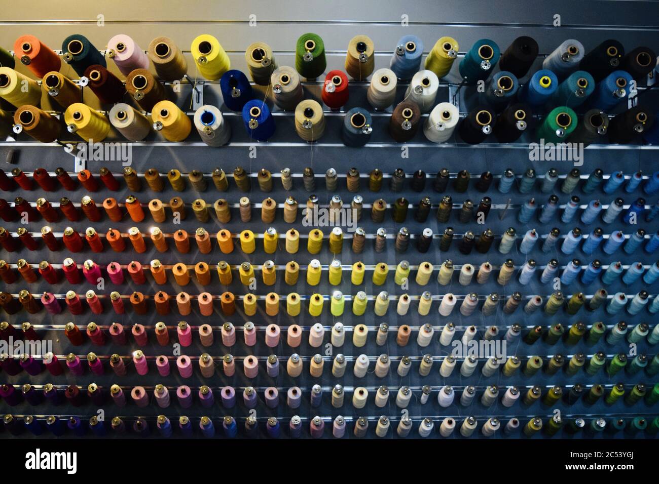 Wall in a sewing shop with colorful spools of thread Stock Photo - Alamy