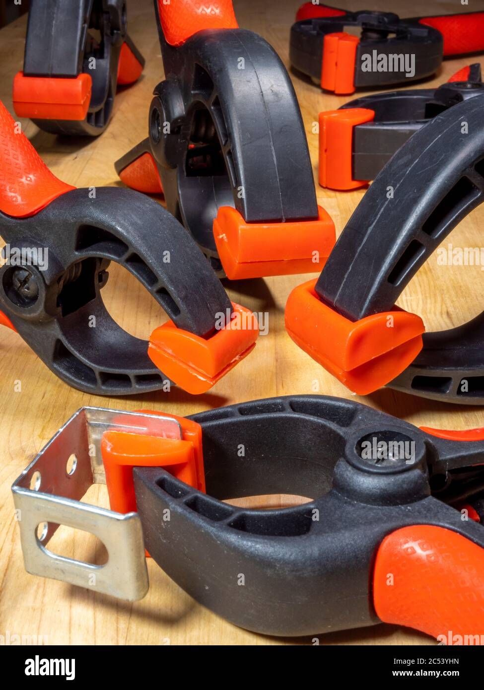 A collection of different sized traditional spring clamps on a bench ...