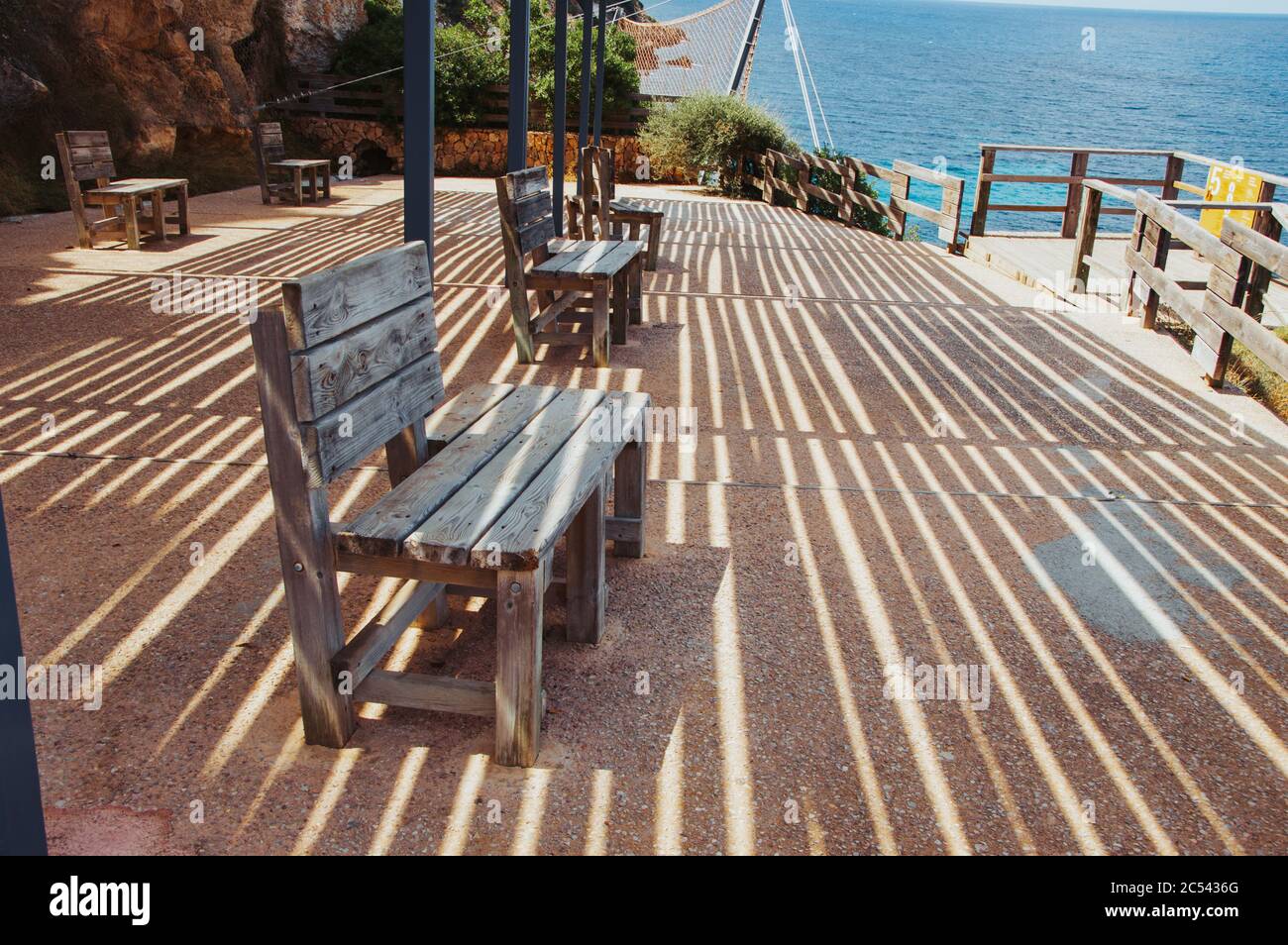 Outdoor wooden benches with spaces for social distancing near the sea ...
