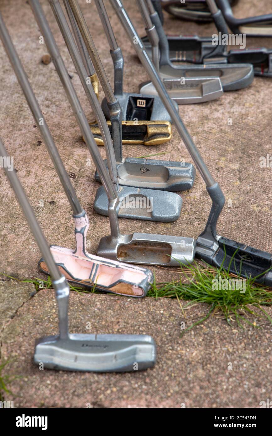 Golf clubs lined up against wall at putting green Stock Photo - Alamy