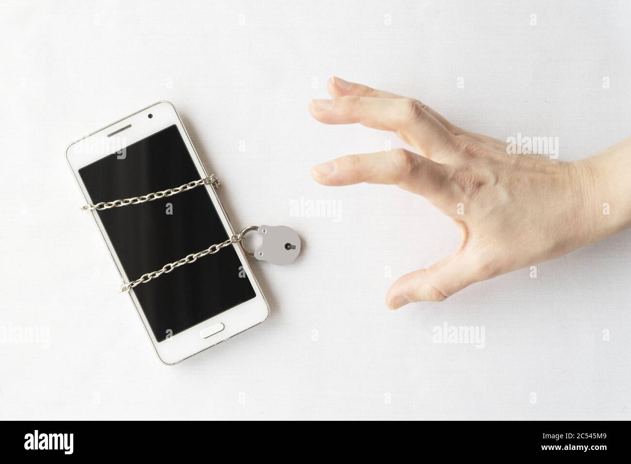 A white phone tied in a chain and a lock showing the concept of phone ...