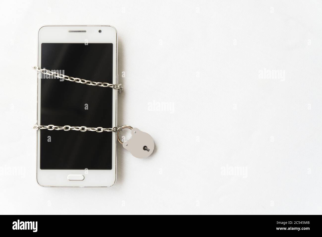 White phone tied in a chain and a lock symbolizing the concept of phone ...