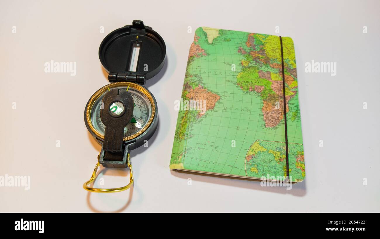Horizontal shot of an antique compass and travel notebook on a white ...
