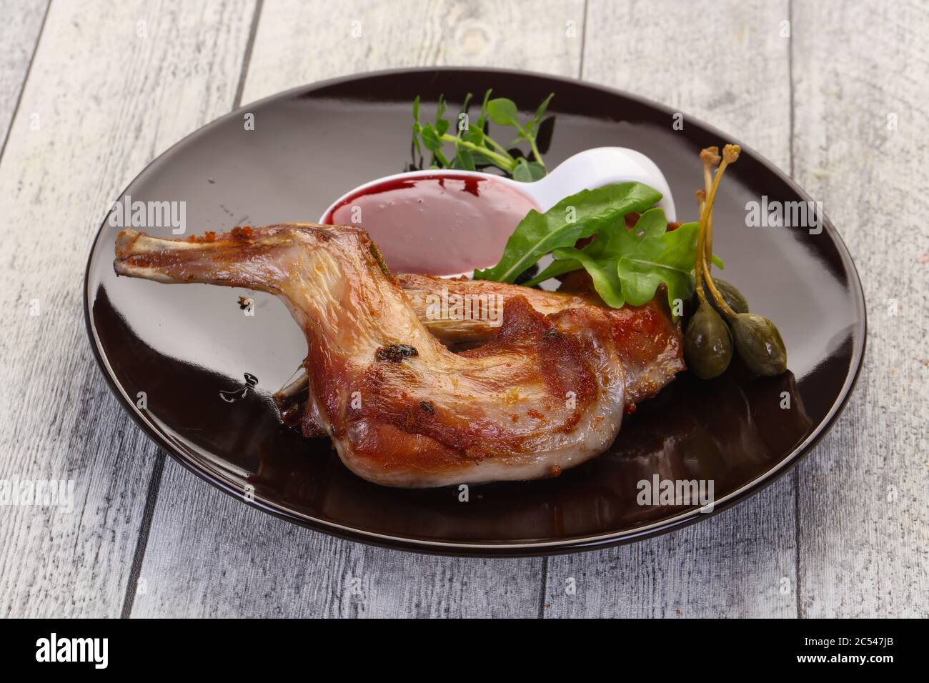 Roasted rabbit legs with cowberry sauce Stock Photo - Alamy