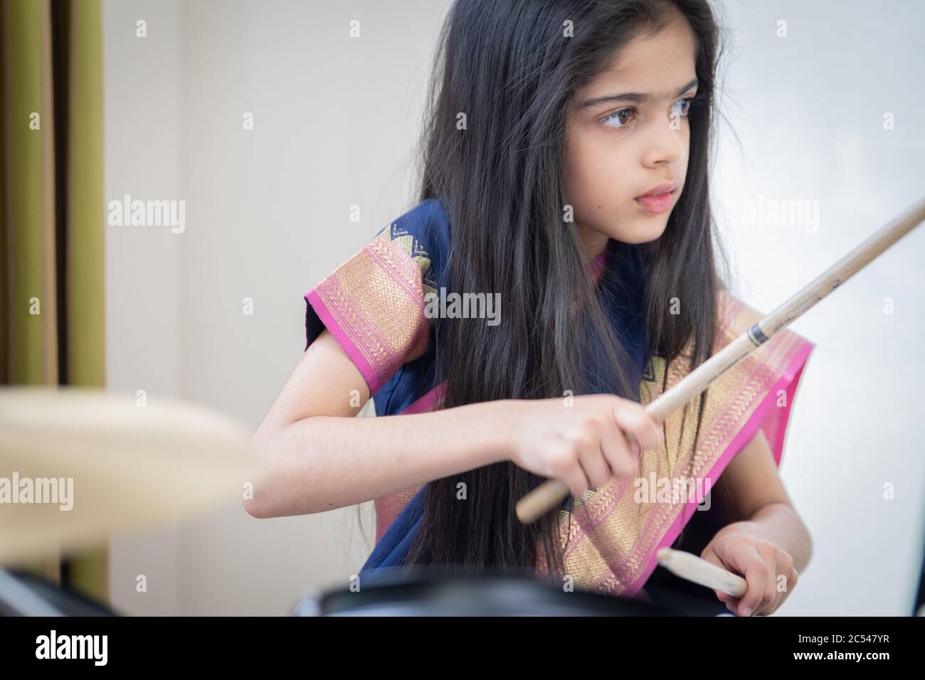 School age British Indian girl playing the drums in a saree Stock Photo ...