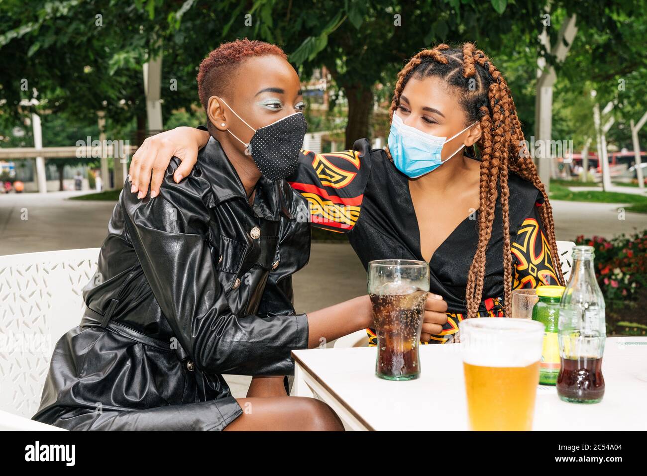 Two multi-racial, black and mixed-race friends on a bar terrace having ...
