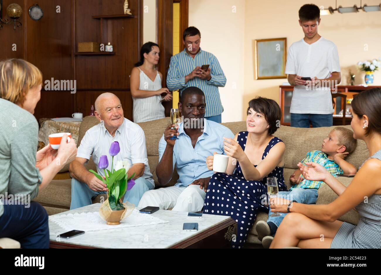 Portrait of big multigenerational family chatting and drinking wine and ...