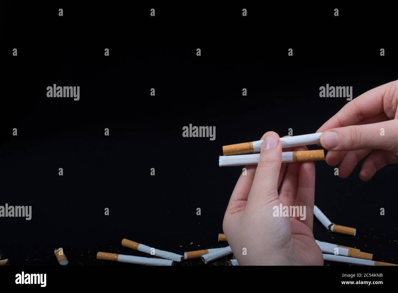 Hand is holding cigarettes on a black background Stock Photo - Alamy