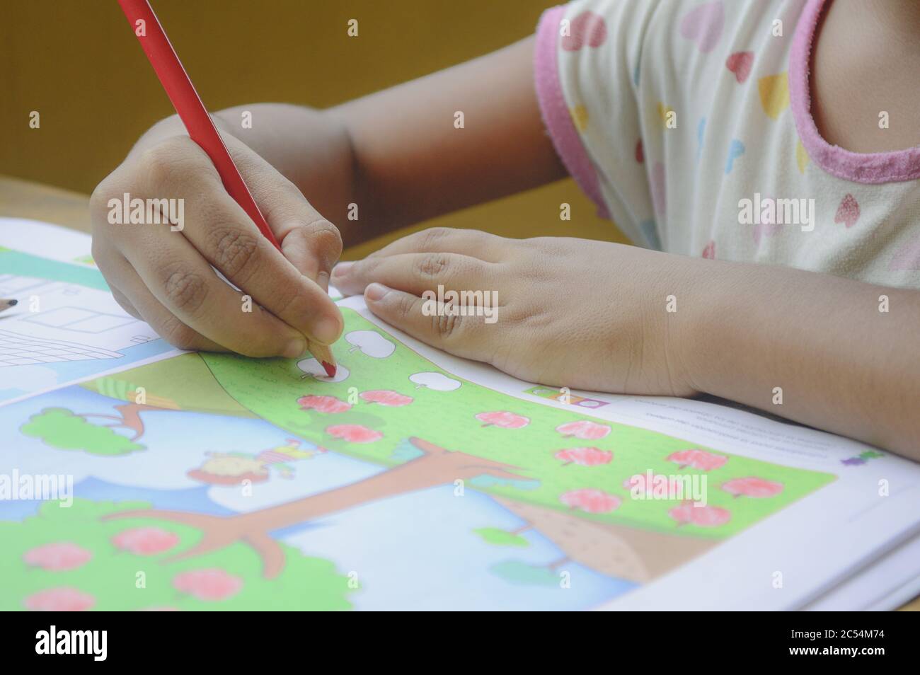 Closeup shot of a girl coloring a picture book using a red pencil Stock ...