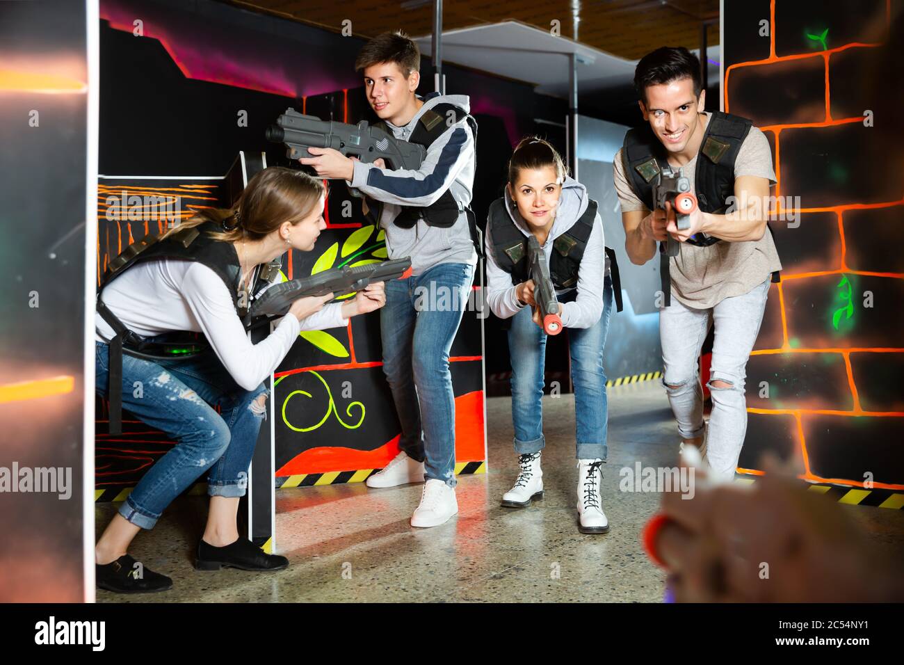 Cheery people aiming laser guns at other players during lasertag game ...