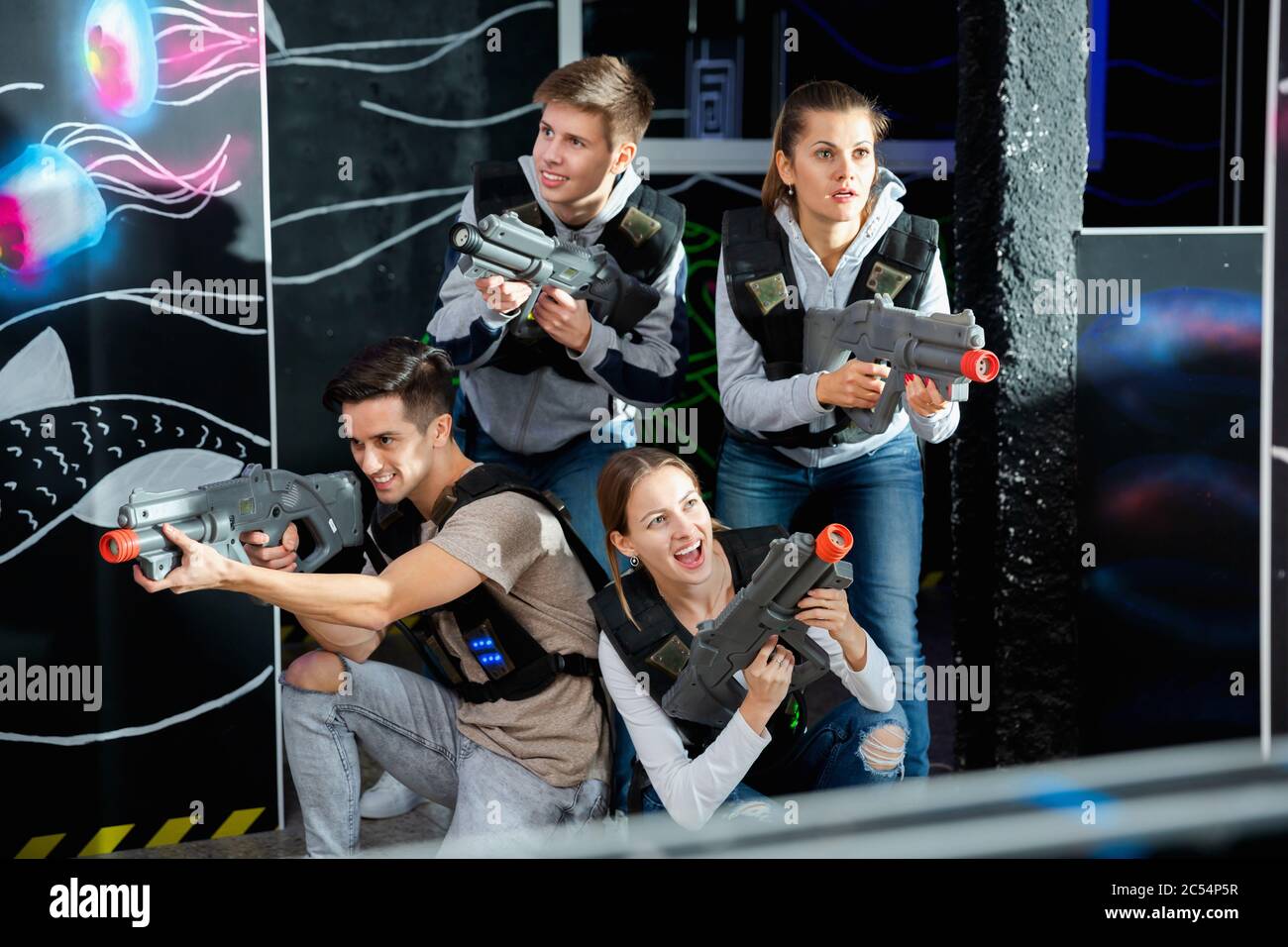 Happy glad cheerful young people with laser pistols posing together on ...