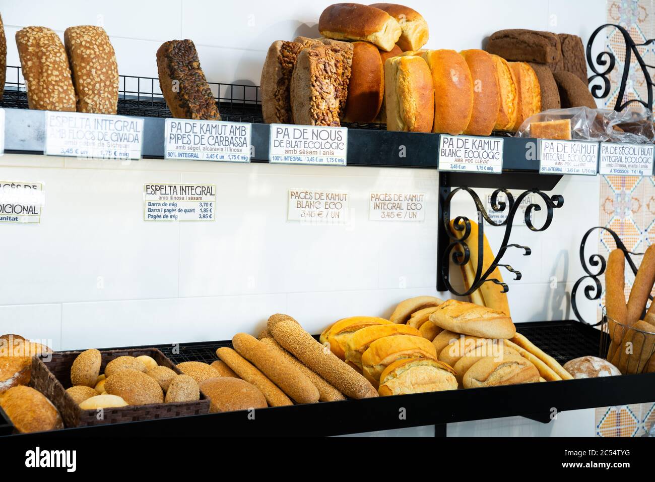 Variety of freshly baked bread, baguettes and buns on shelves in bakery ...