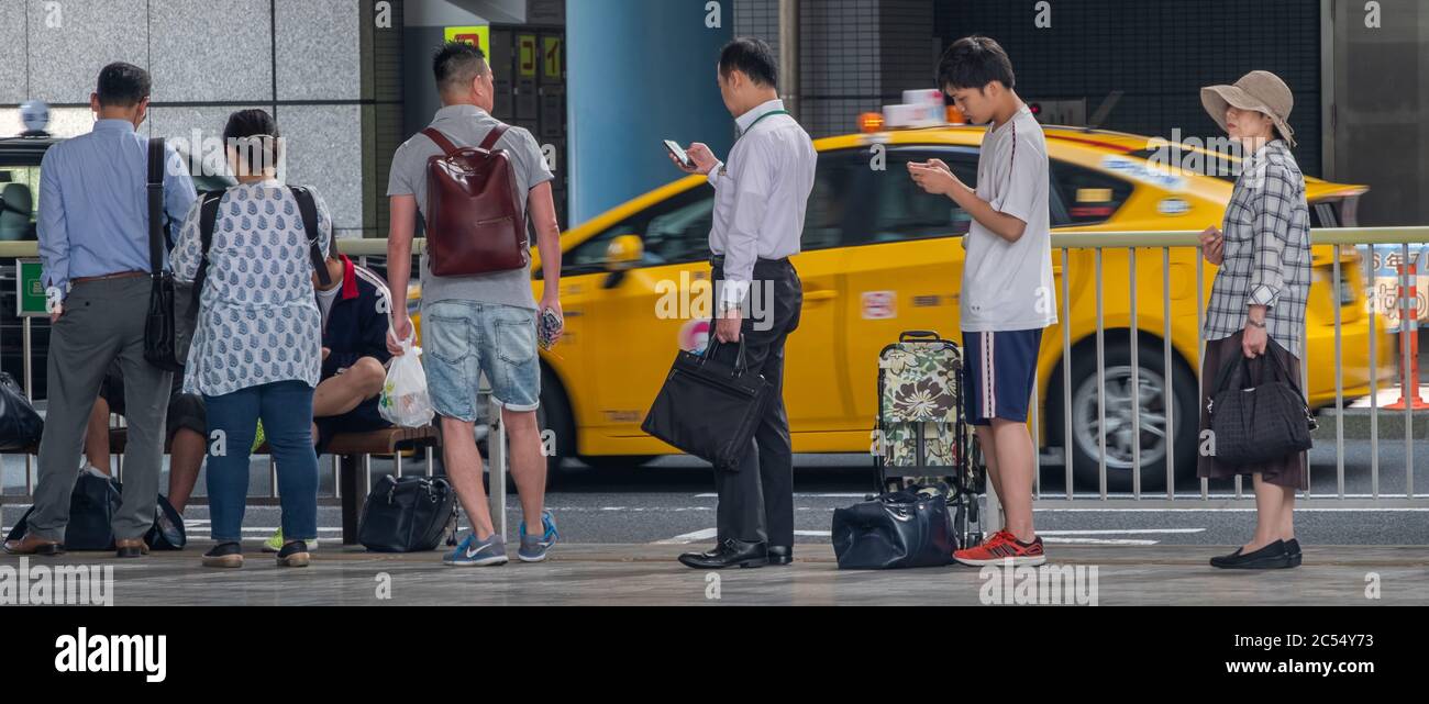 Office workers lining up waiting to board a bus at Shinagawa Station ...