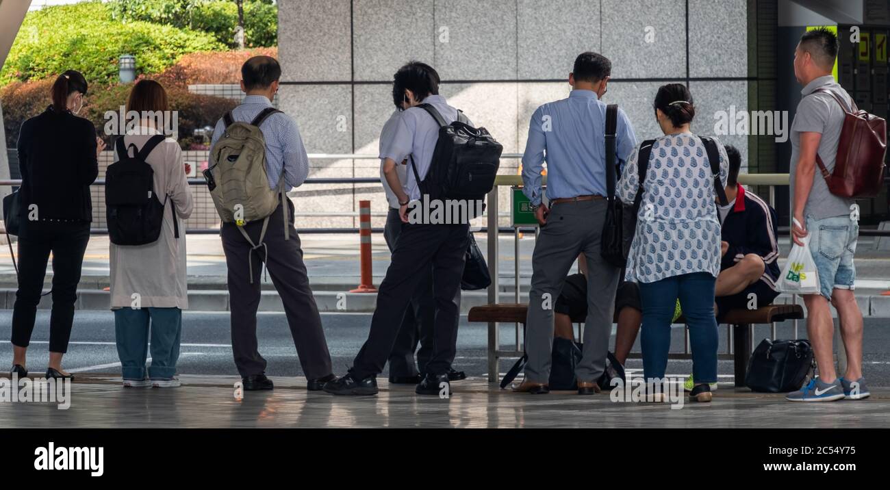 Office workers lining up waiting to board a bus at Shinagawa Station ...