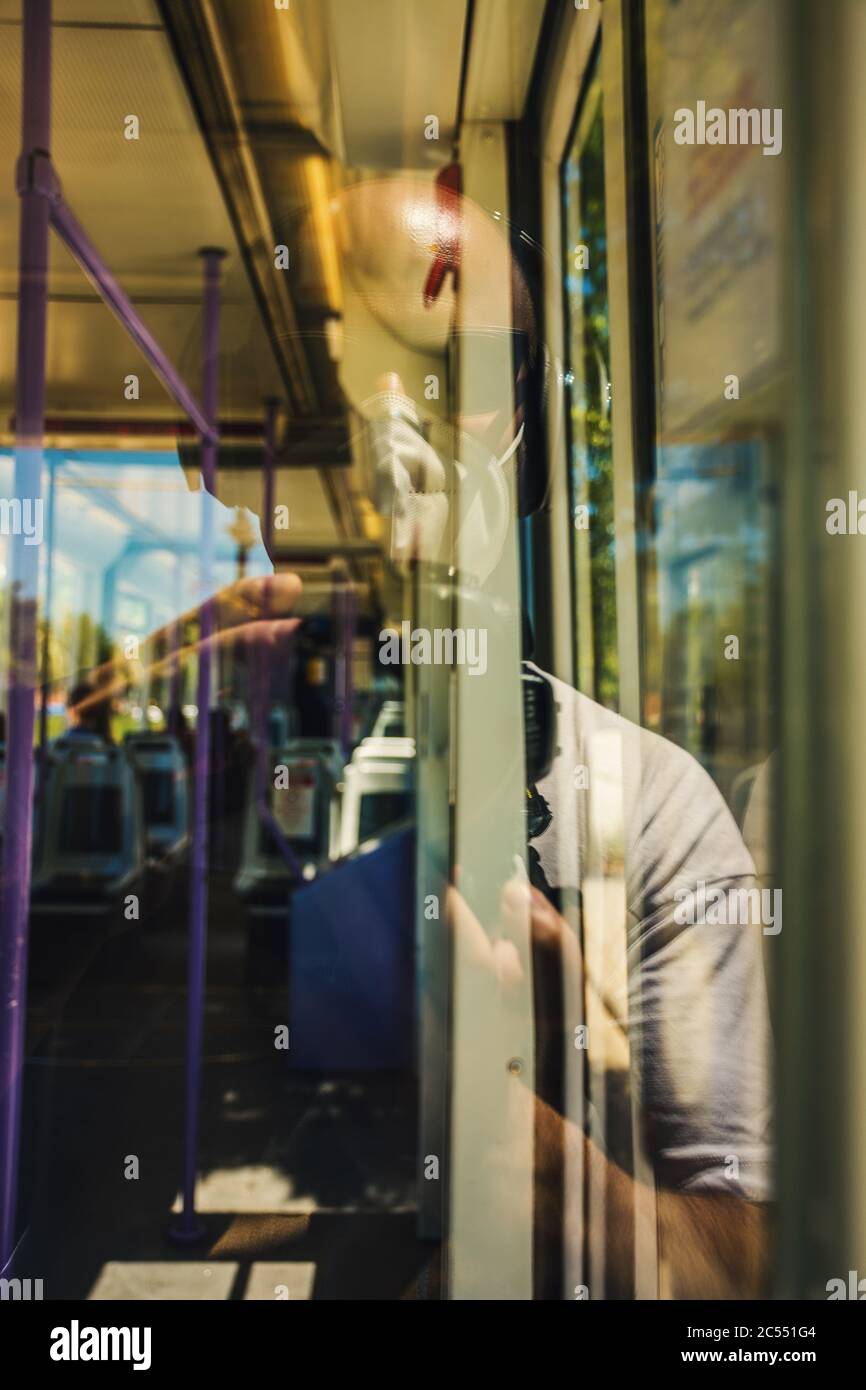 Vertical shot of a male's reflection on bus windows wearing a medical ...