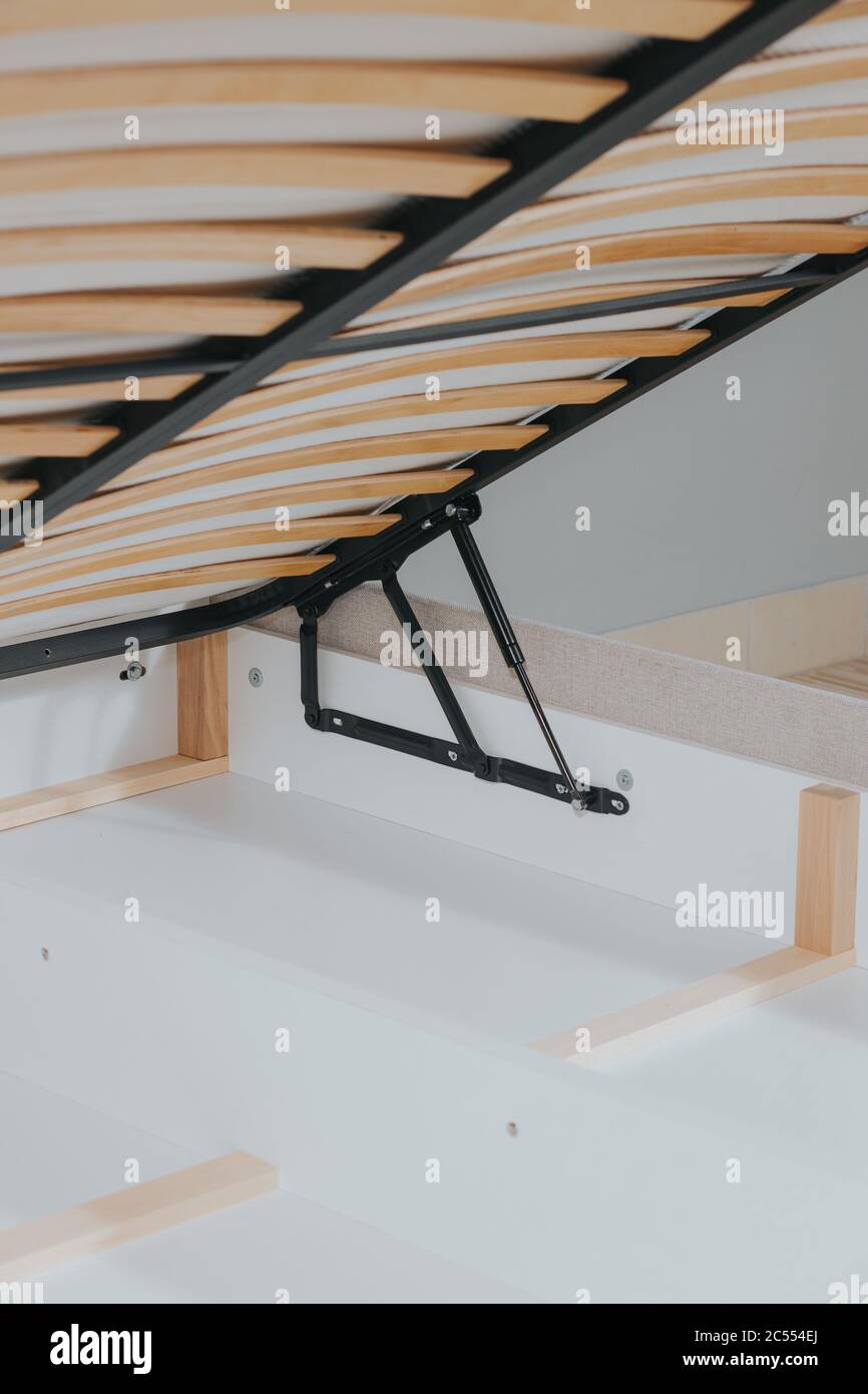 Vertical shot of a bed with wooden frame and lifting mechanism for a ...