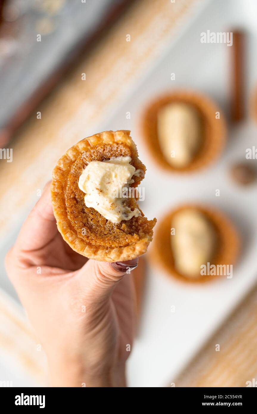 Bitten mini sugar pie in hand. Mini sugar pies (or butter tarts) with a ...