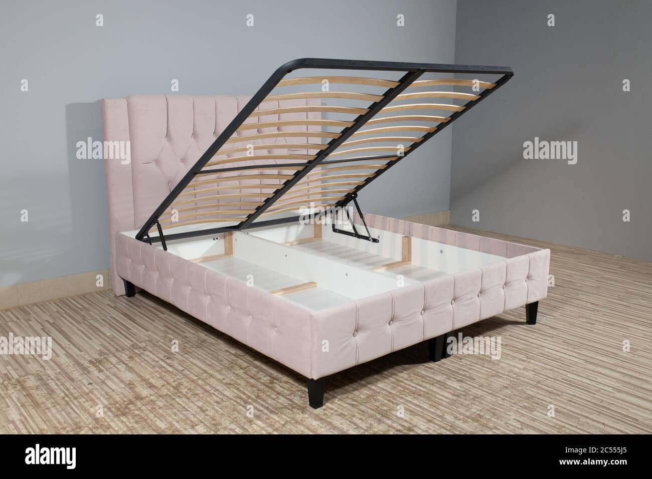 Pink bed with a storage space revealed by lifting the wooden slatted ...