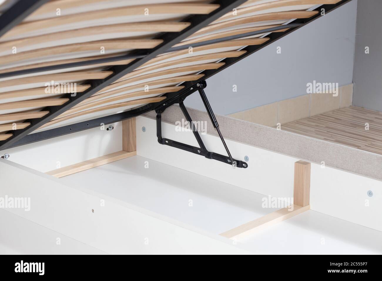 Closeup shot of a bed with wooden frame and lifting mechanism for a ...