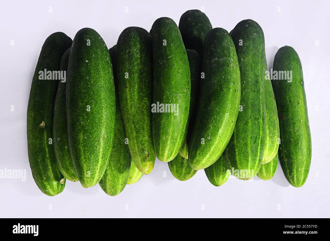 Horizontal shot of a stack of cucumbers places vertically on a white ...