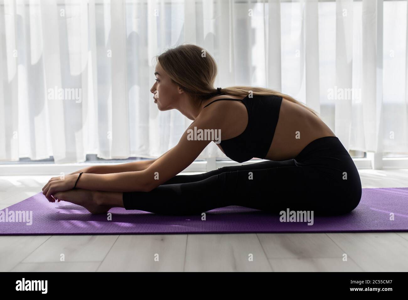 Side view of a professional woman exercising and stretching her body ...