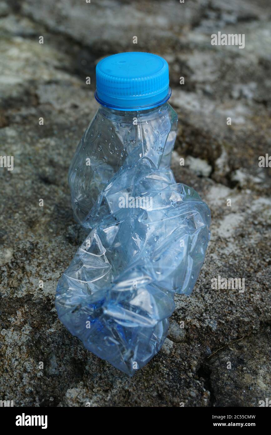 High angle shot of a crushed empty water bottle on a stone surface ...