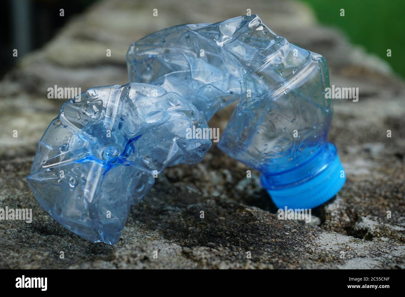 High angle shot of a crushed empty water bottle on a stone surface ...