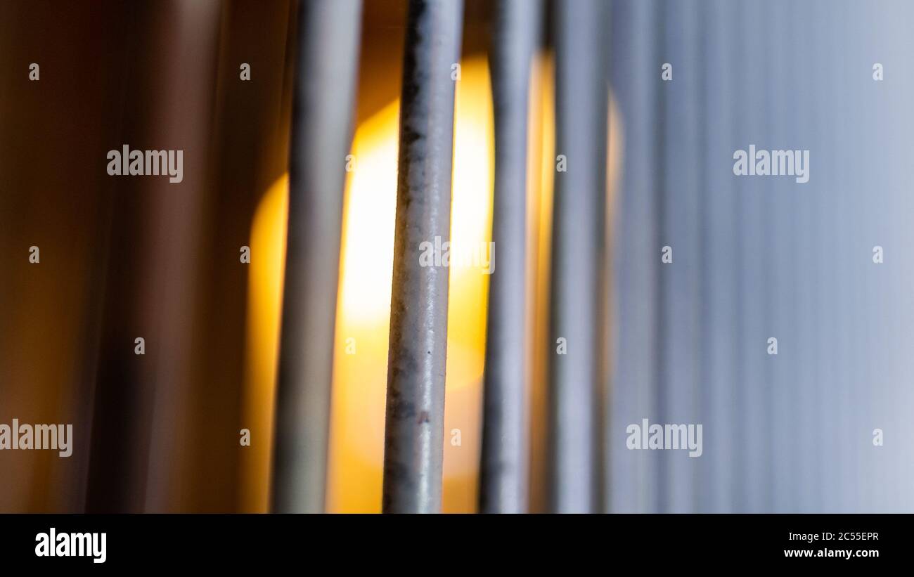 Selective focus shot of grey cage bars and the street lights seen among ...