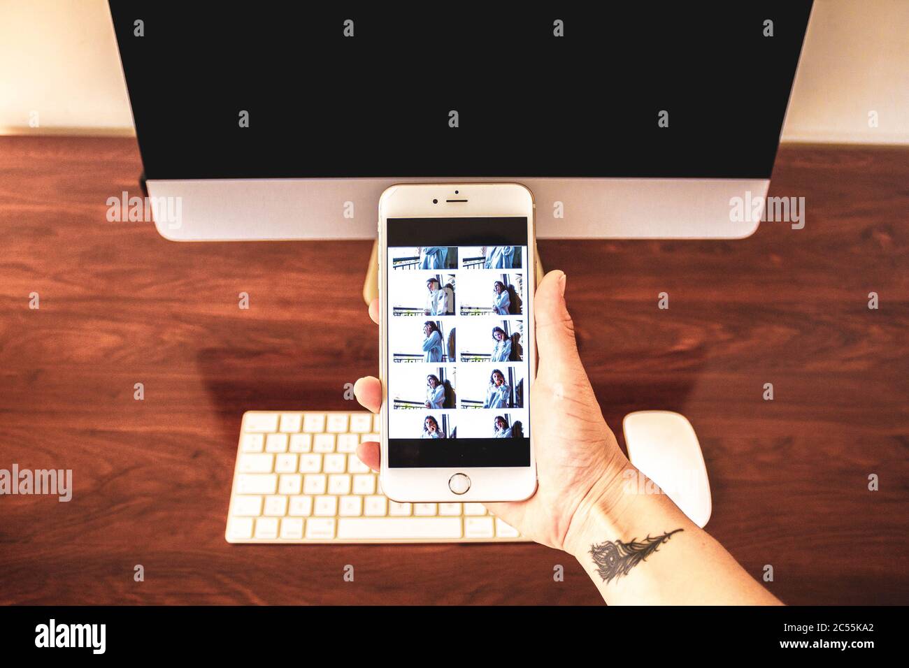 hand holding a mobile phone in front of computer Stock Photo - Alamy