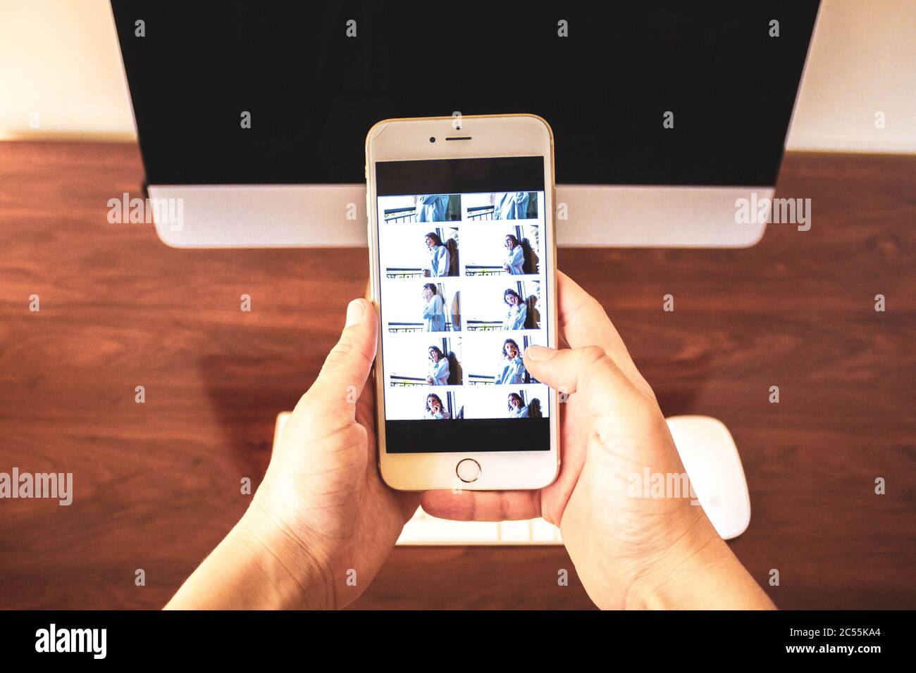 hand holding a mobile phone in front of computer Stock Photo - Alamy