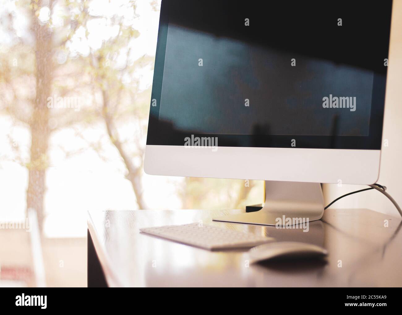 desktop computer on wooden table against light window with trees Stock ...