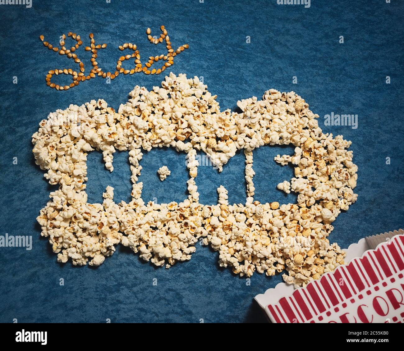 Spilled popcorn bucket with the a Stay Home message on a blue ...