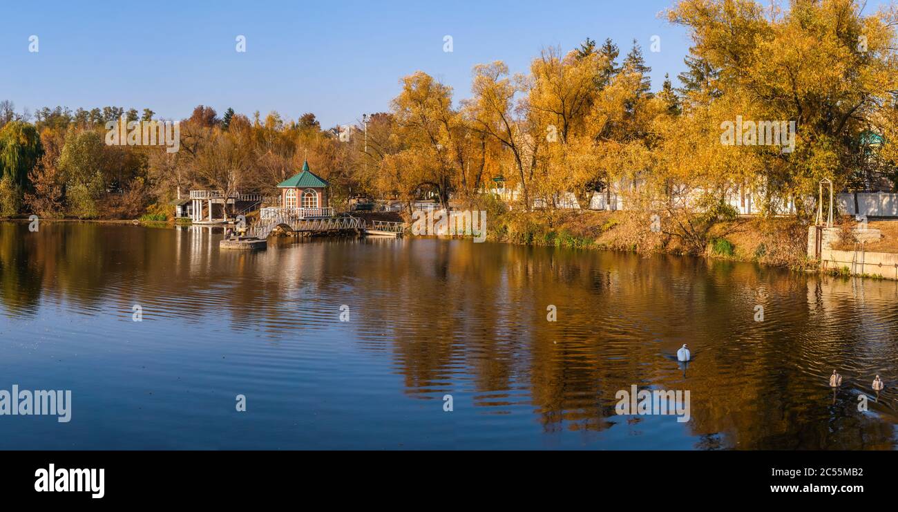 Sunny autumn evening on the blue lake with yellow trees. The Ivanki ...
