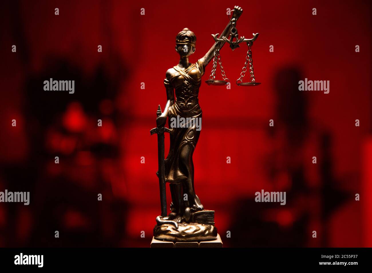 Closeup shot of lady justice bronze statue isolated on a red background ...
